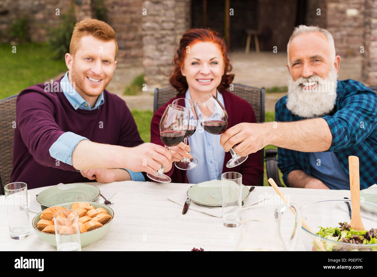 parents and adult son clinking glasses of wine while having dinner ...