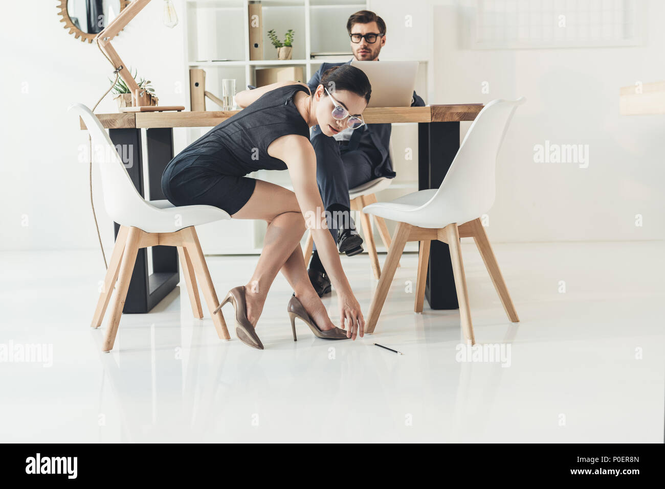 Young businesswoman leaning gracefully to pick up pencil from the floor ...