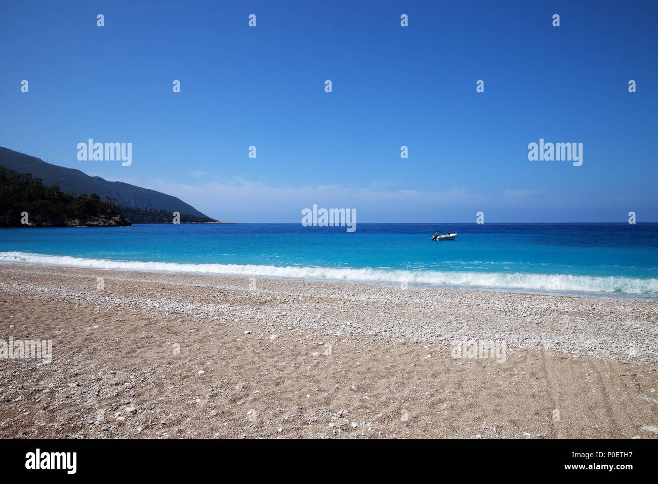 Sand beach with pebble stones and beautiful blue sea at warm sunny ...