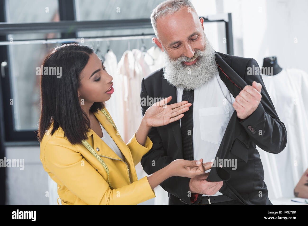 young stylist talking with grey haired client in suit indoors Stock ...