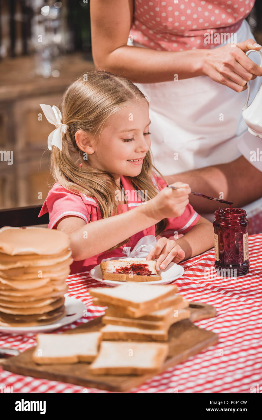 cute smiling little girl eating delicious toast with jam for breakfast ...
