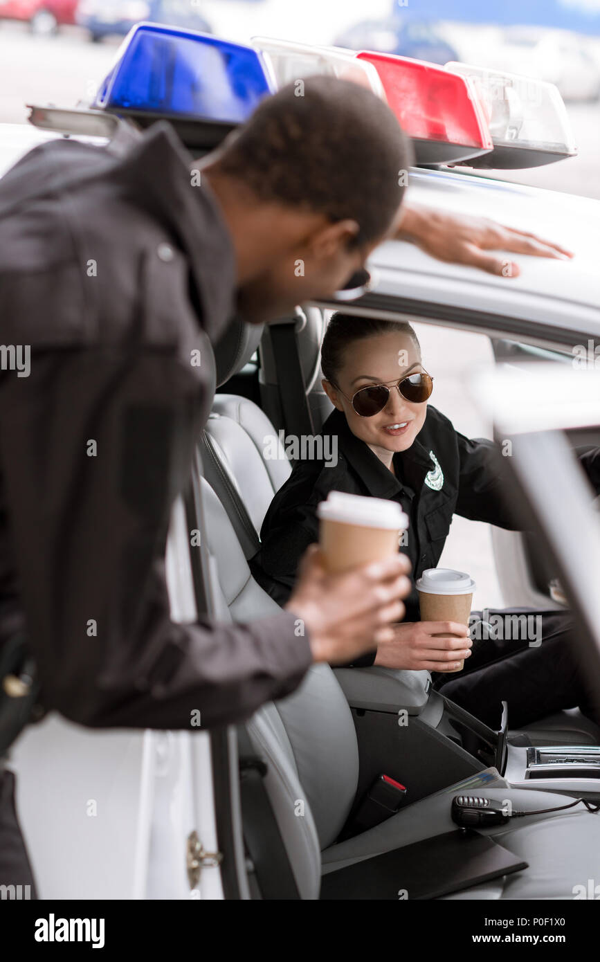 young police officers with car drinking coffee to go Stock Photo - Alamy