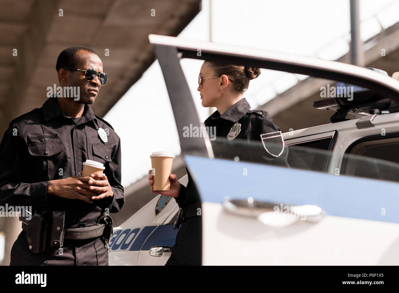 young relaxing police officers drinking coffee near police car Stock ...
