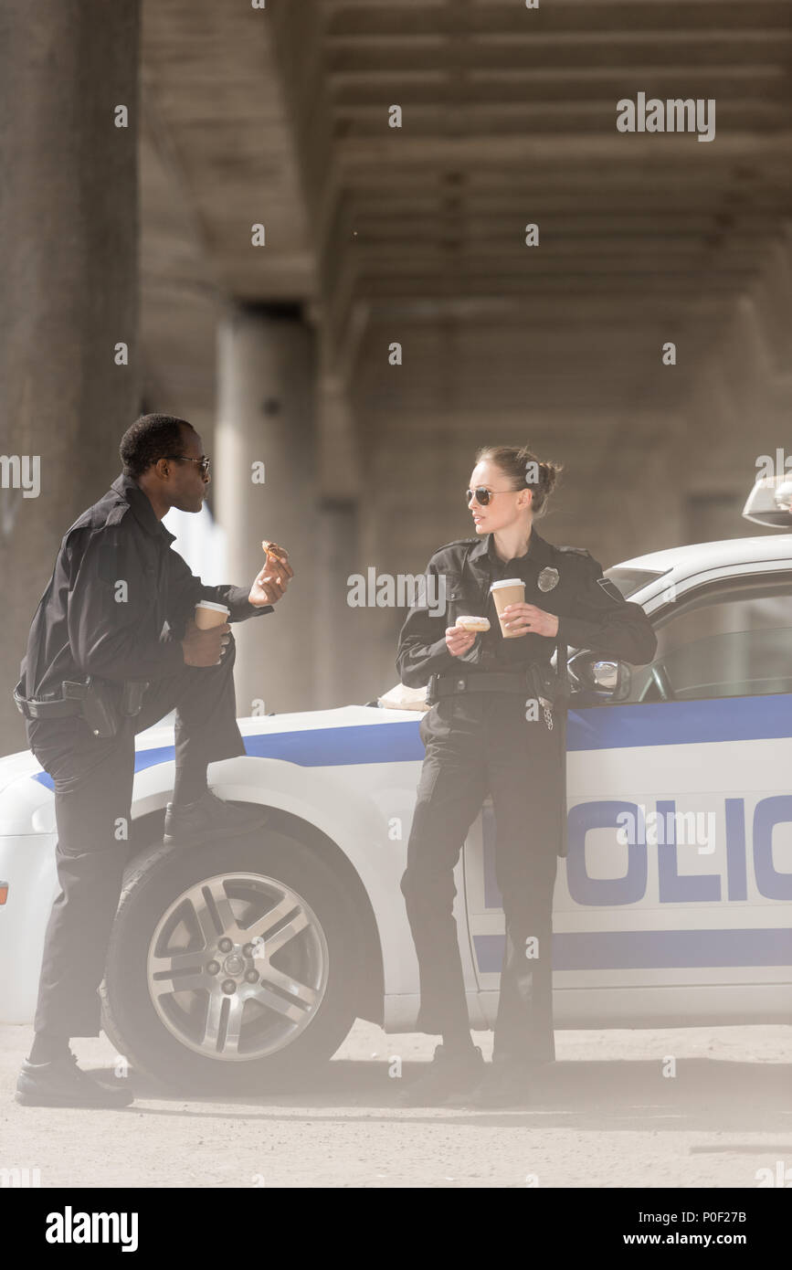 police officers with coffee and doughnuts standing next to car under ...