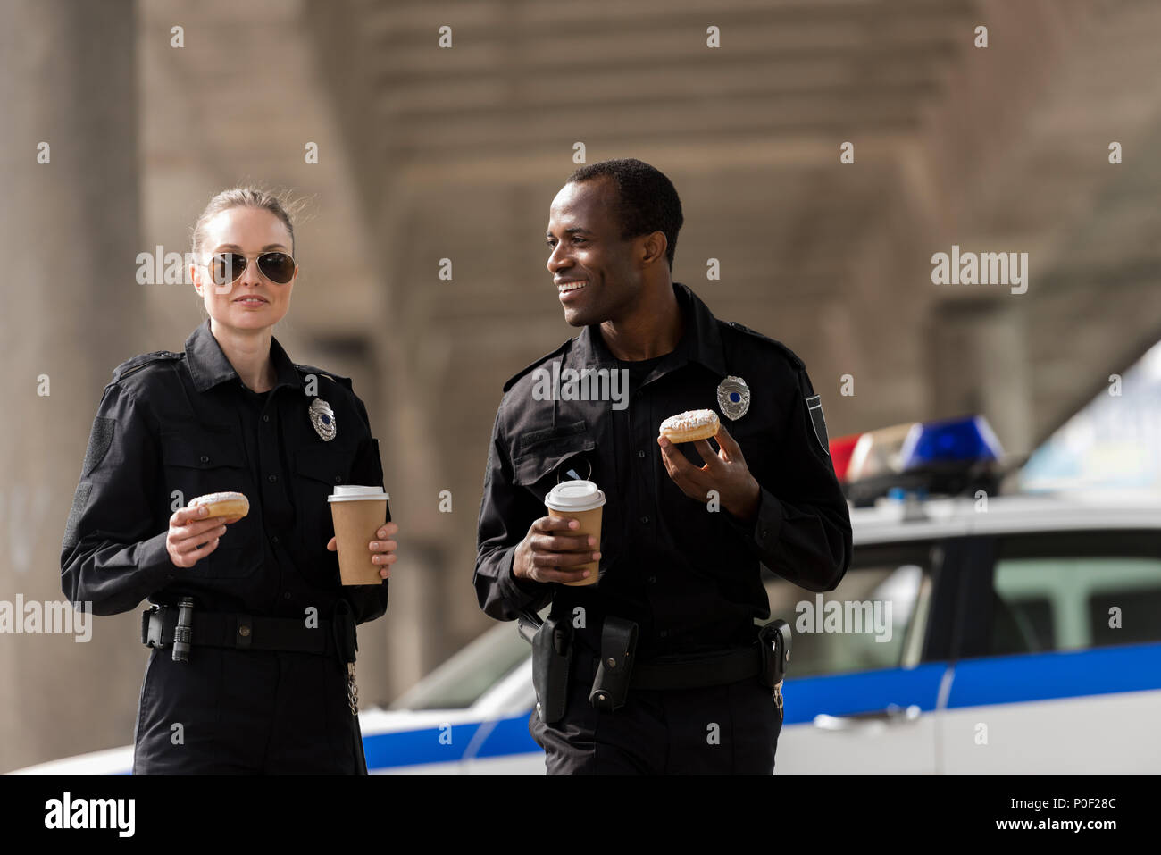 smiling police officers having coffee break with doughnuts Stock Photo ...
