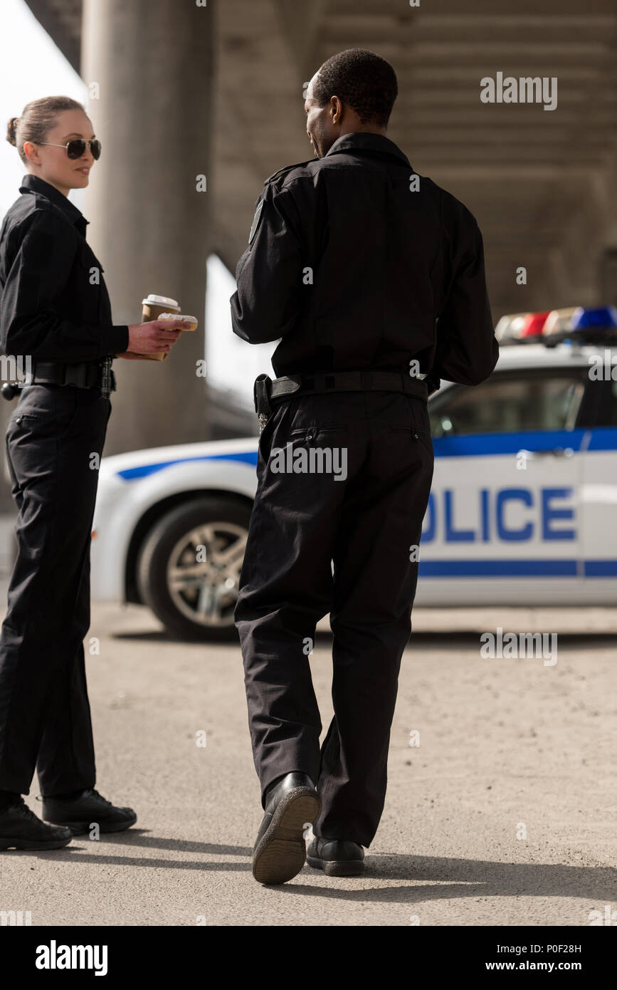 smiling police officers having coffee break and chatting in front of ...