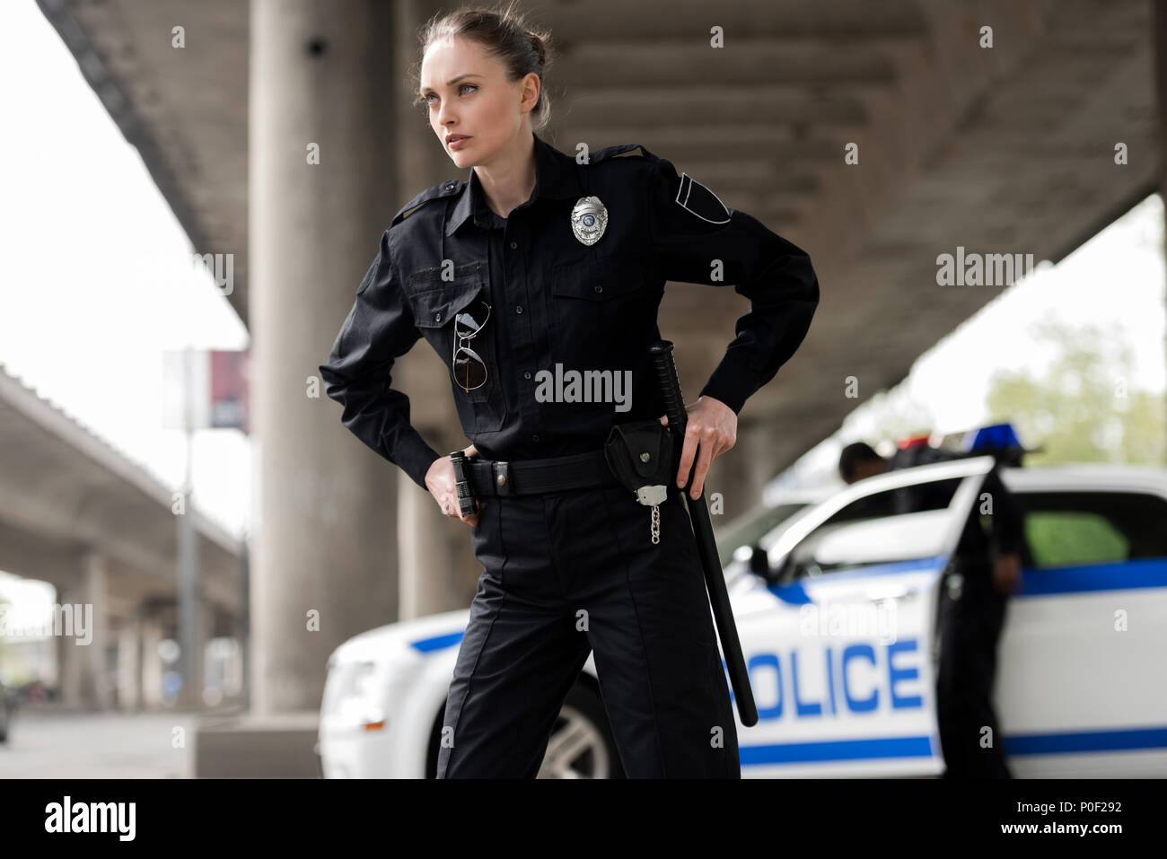 confident female police officer looking away and taking out gun and bat ...