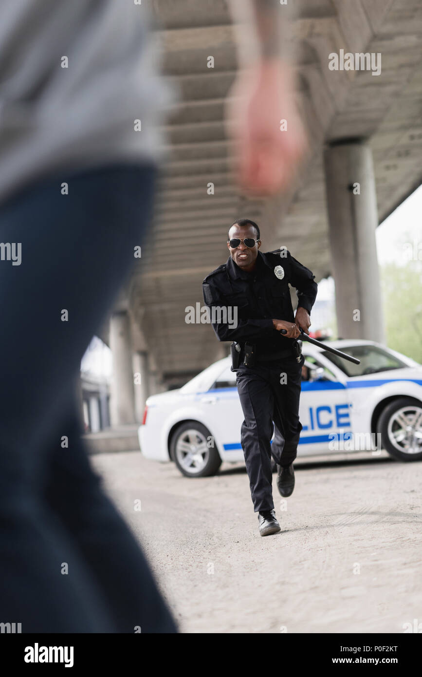 cropped shot of thief running from african american policeman Stock ...