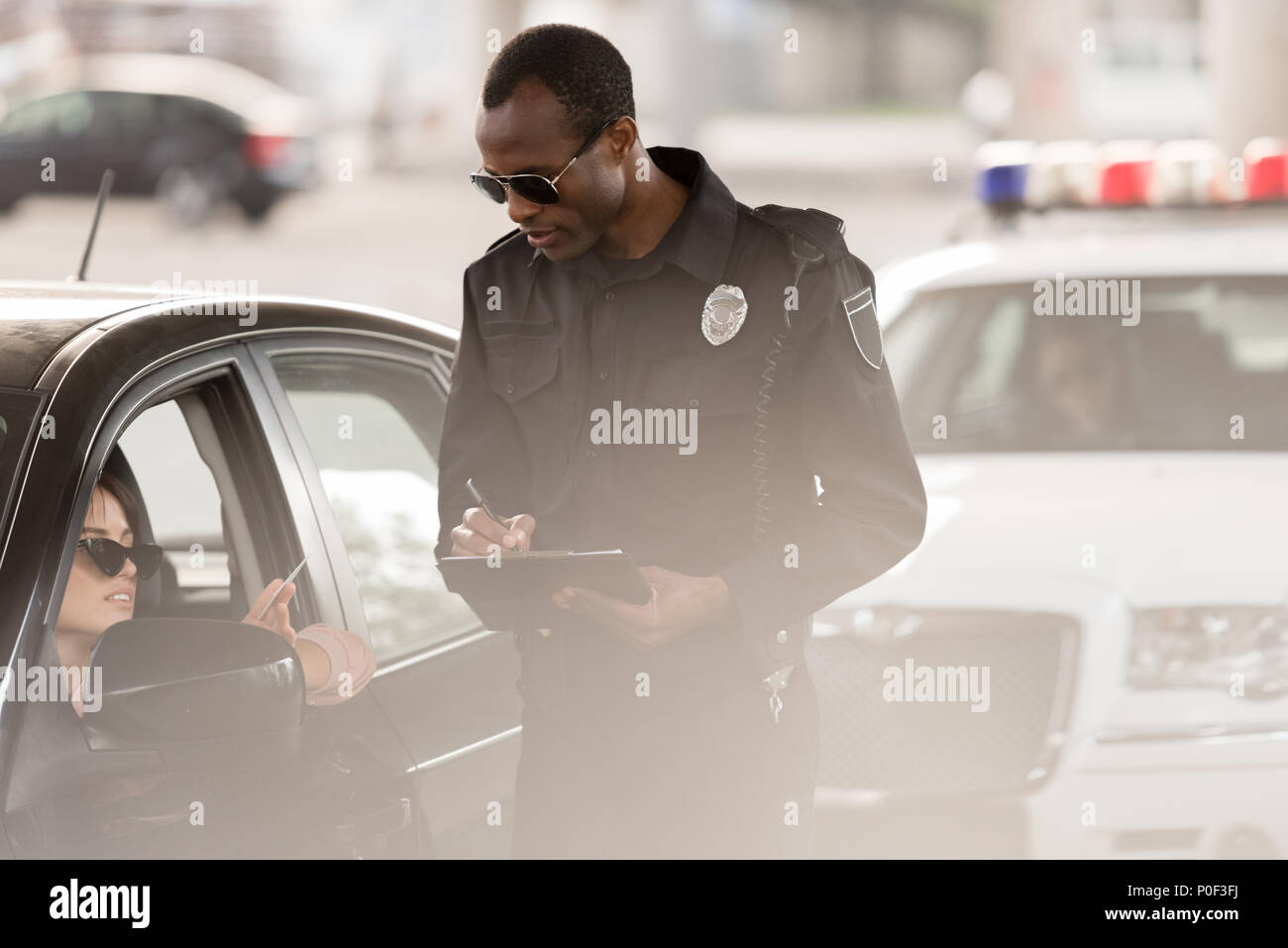 young woman in car giving driver license to african american policeman ...