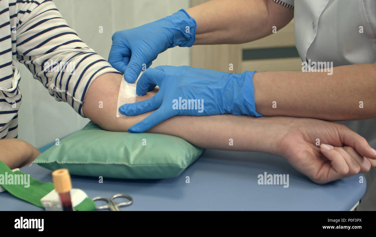 Nurse putting plaster on female arm after blood donation Stock Photo ...