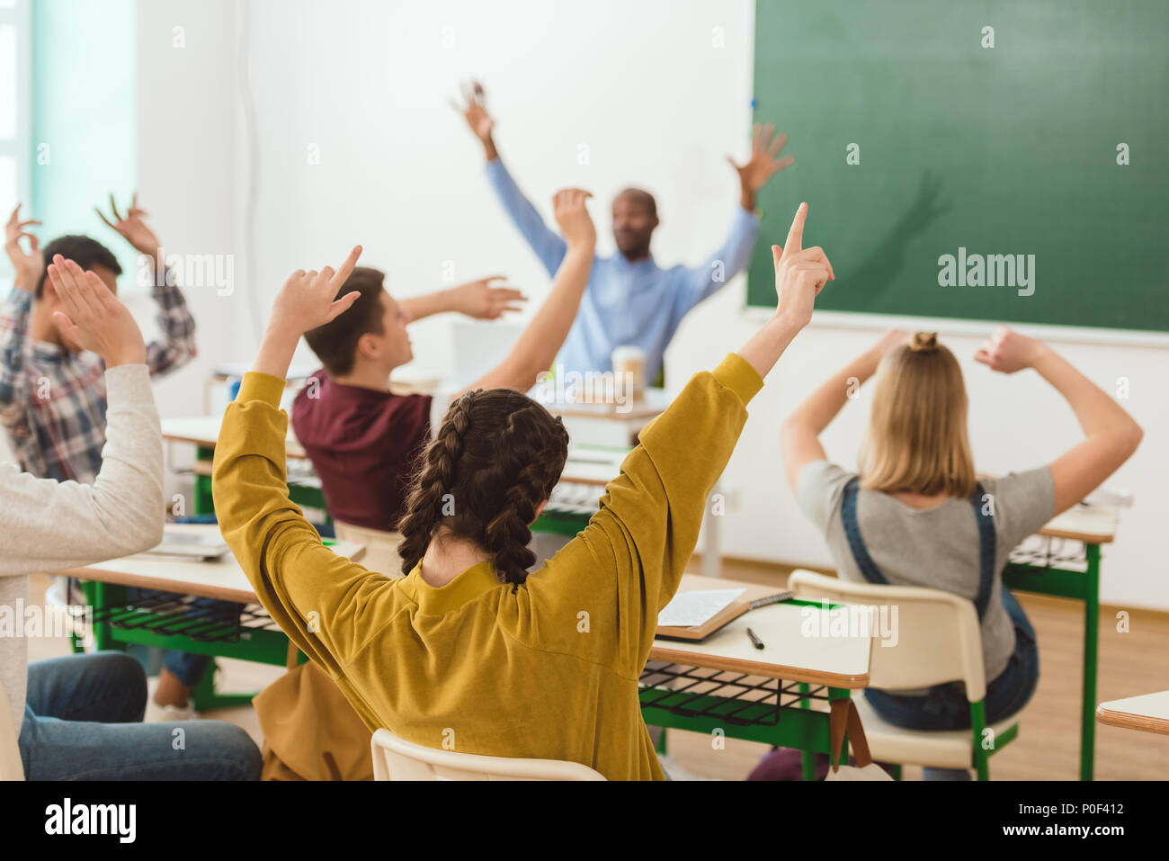 Rear view schoolchildren and teacher resting with raising arms Stock ...