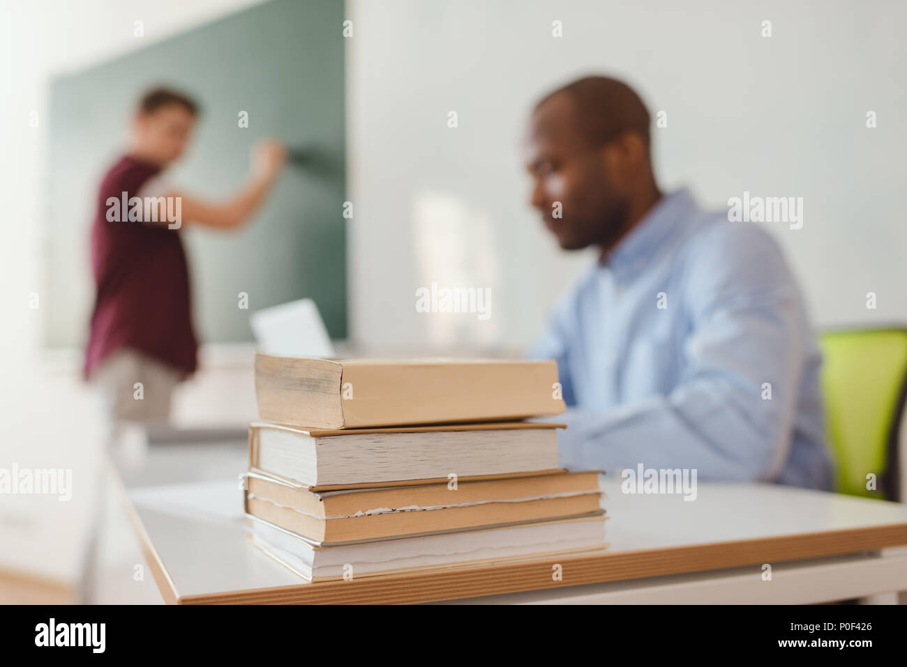 Close up shot of stack of books with teacher and high school student on ...