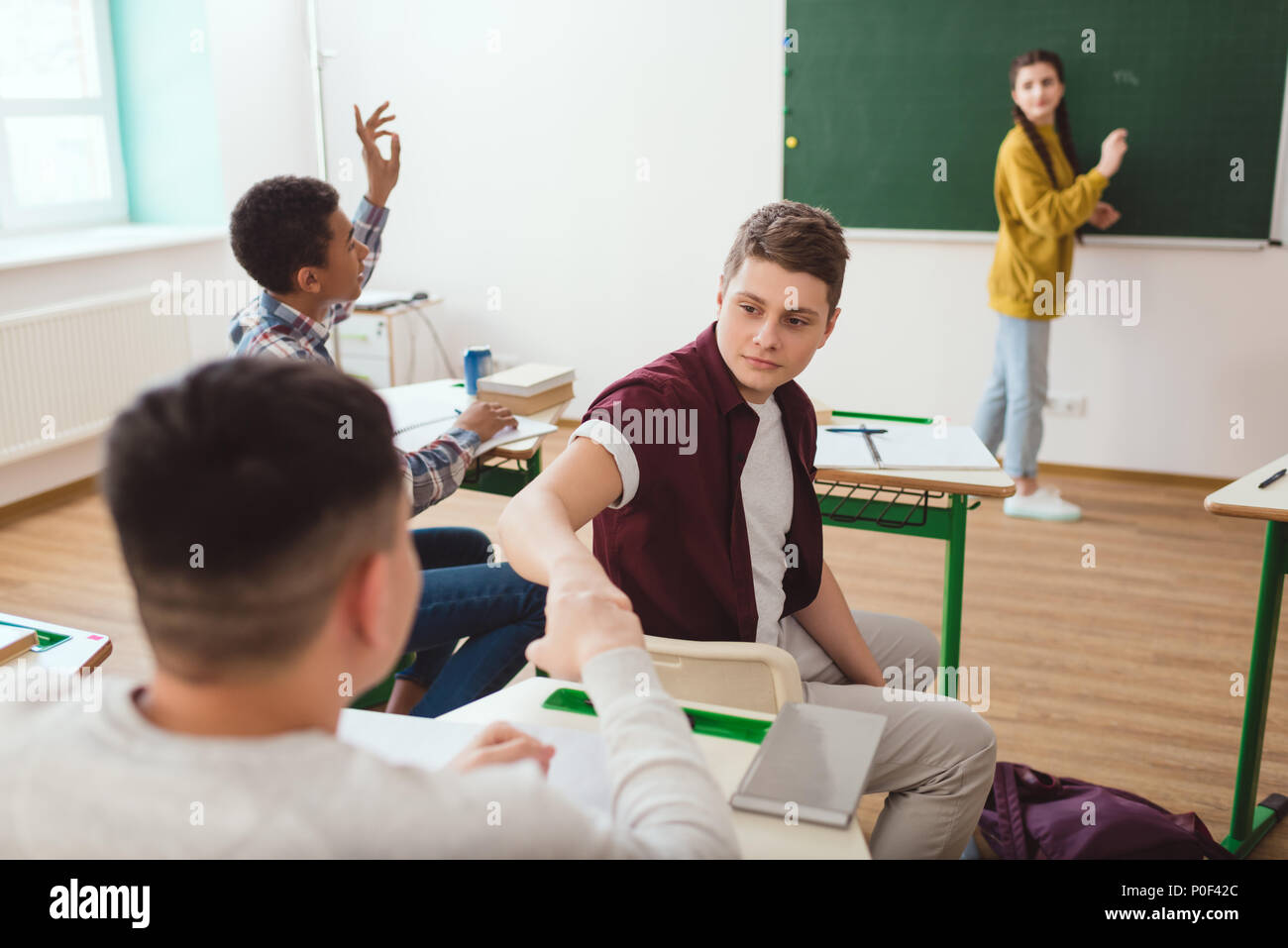 Multicultural high school students doing fist bump and classmates ...