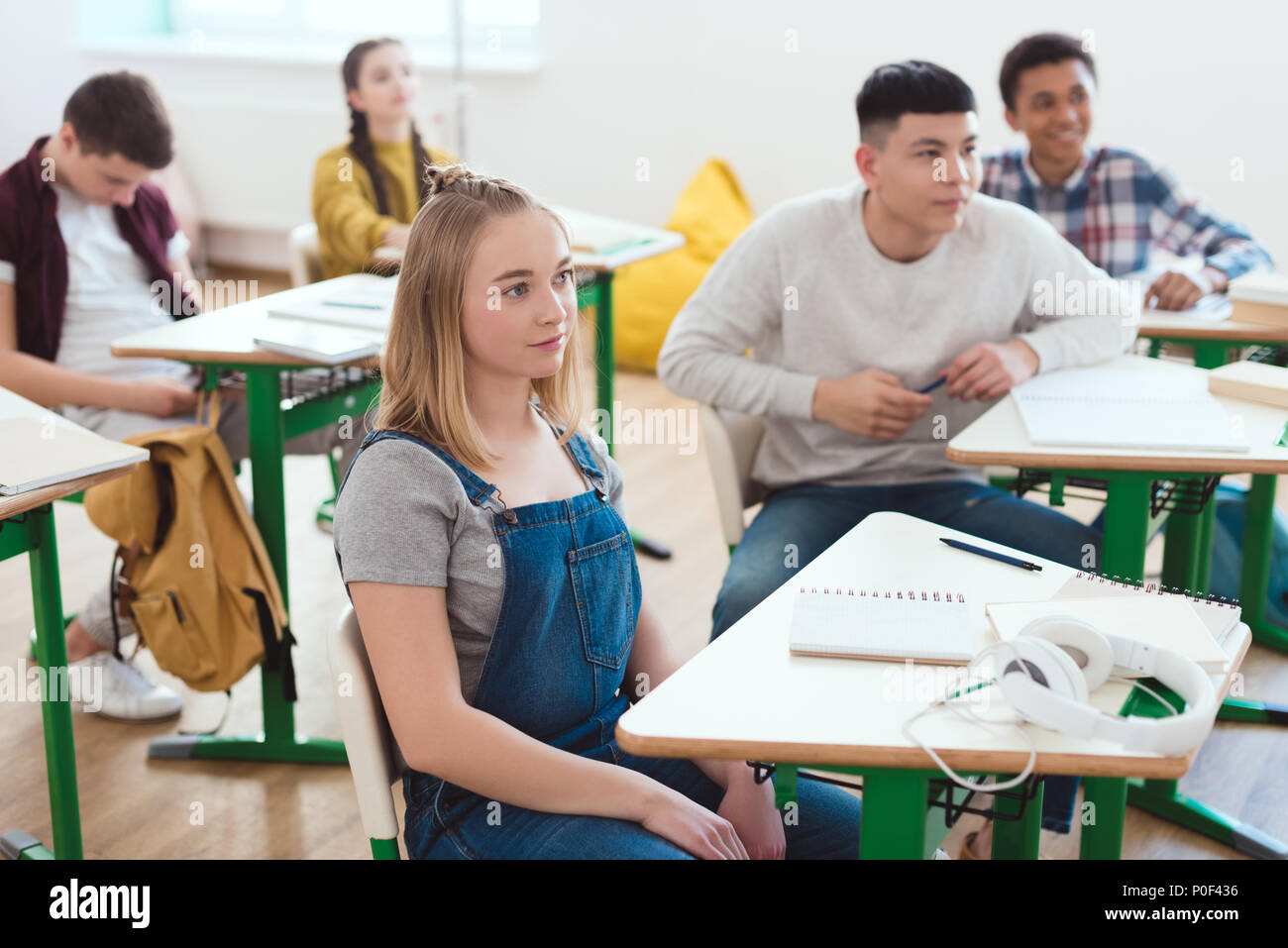 Group of multicultural teenage high school students sitting in ...