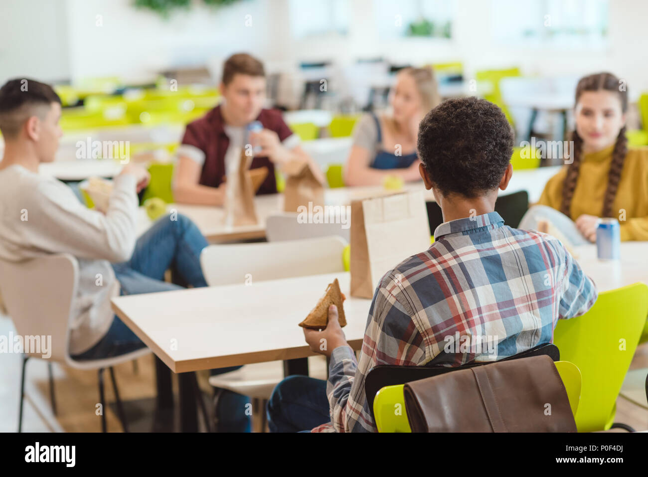 group of teen students chatting while taking lunch at school cafeteria ...