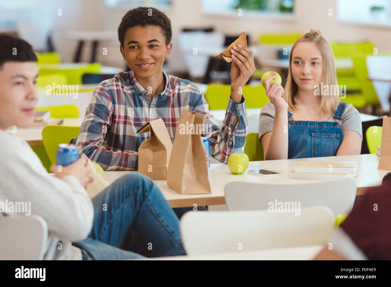 multiethnic group of high school students chatting while taking lunch ...