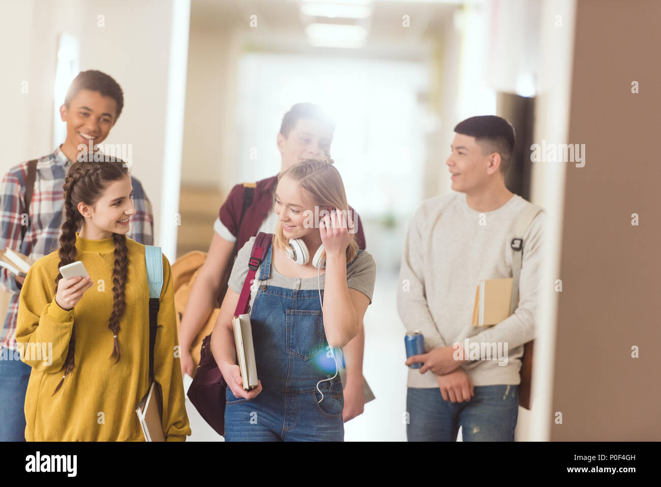 group of high school classmates spending time at school corridor ...