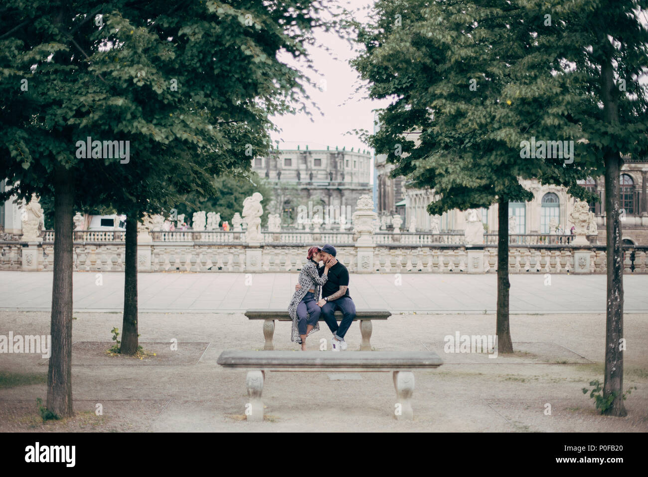 beautiful stylish young couple hugging and kissing on bench in Dresden ...