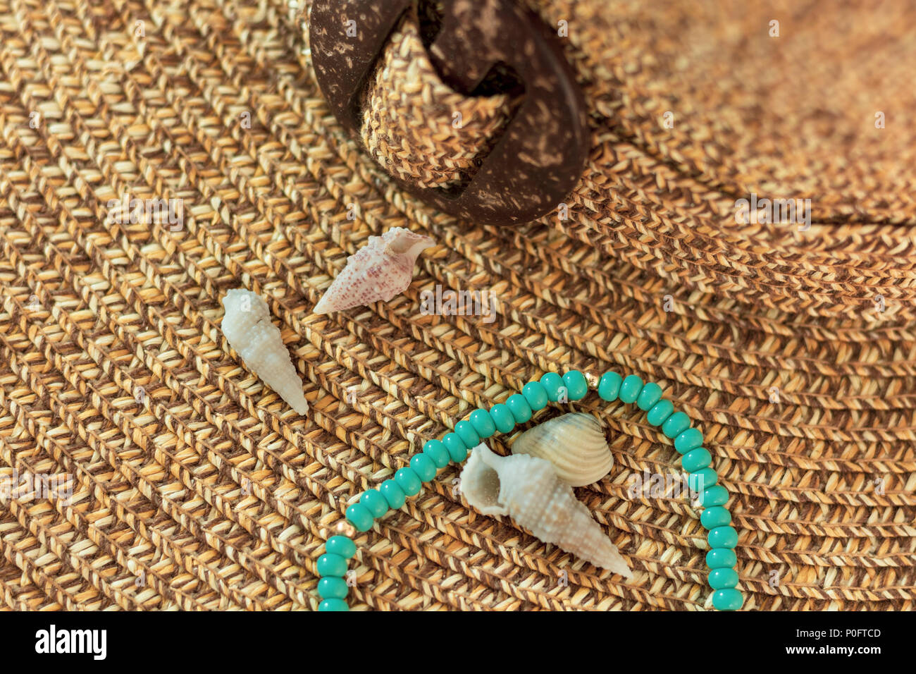 tiny seashells and bracelet on woven hat. The smooth texture of the ...