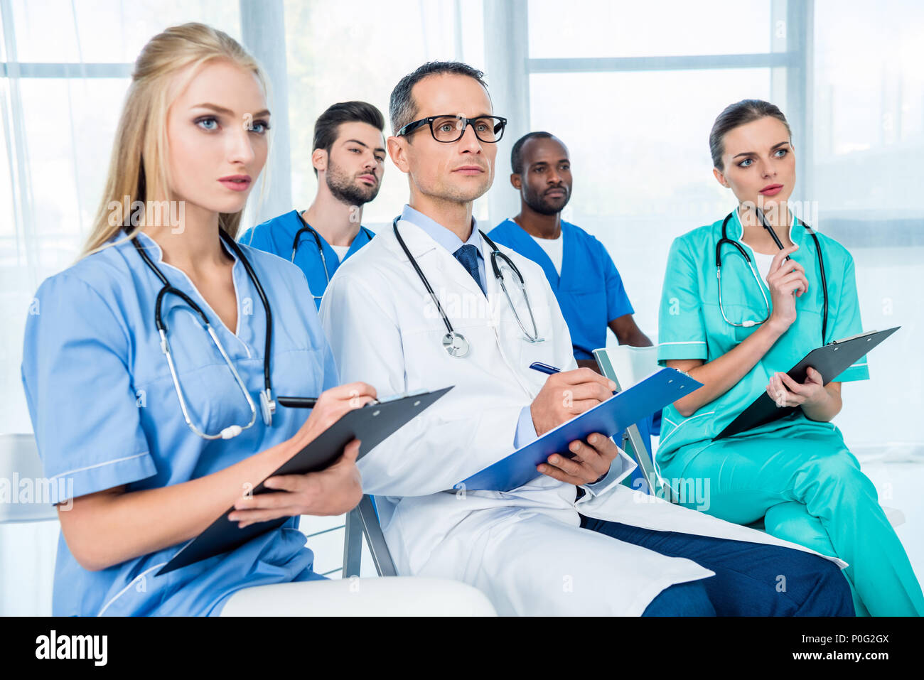 concentrated group of doctors listening to lecture and writing in ...