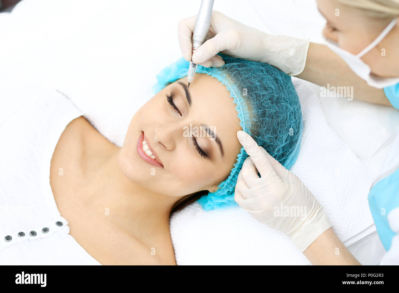 Professional beautician doing eyebrow tattoo at woman face. Permanent ...