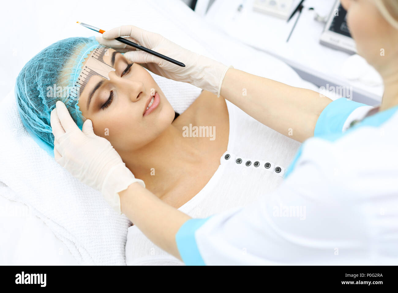 Professional beautician is going to correct eyebrow line at woman face ...