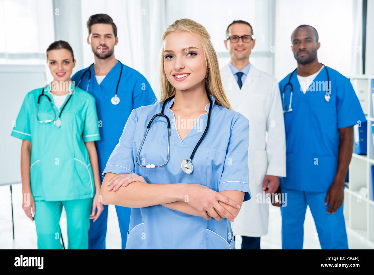 beautiful young nurse with crossed arms with colleagues standing ...