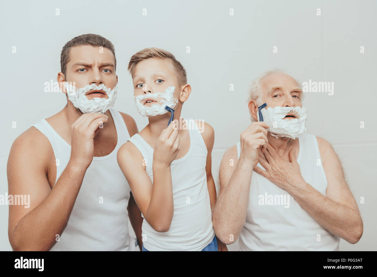 Father, son and grandfather standing with shaving cream on their faces ...