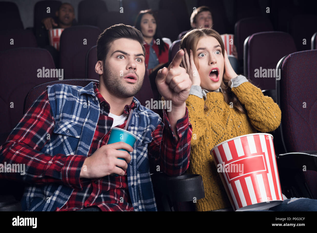 young scared couple with popcorn watching movie in cinema Stock Photo ...
