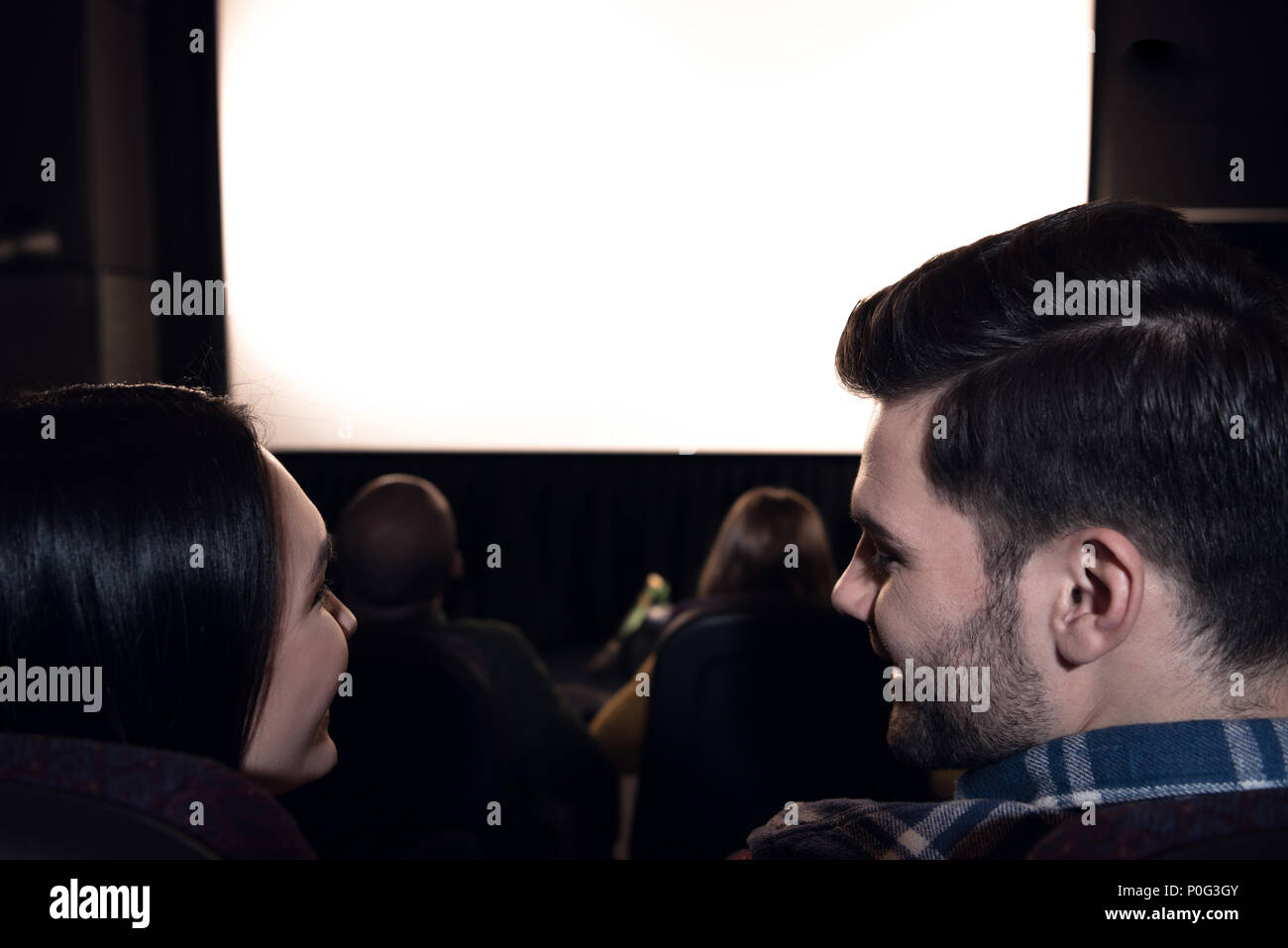 rear view of friends sitting in cinema with white blank screen Stock ...