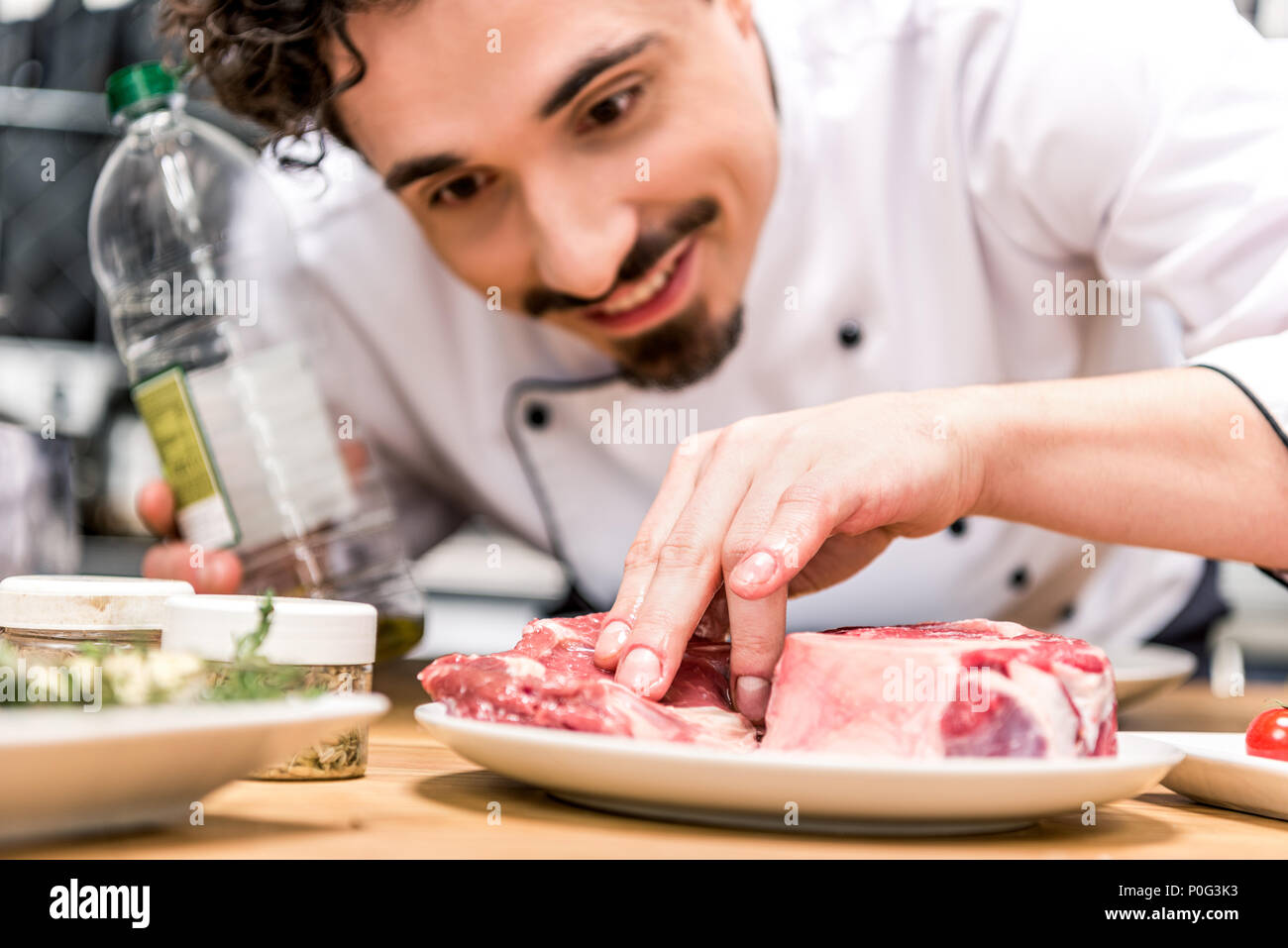 smiling chef adding oil to raw meat Stock Photo - Alamy