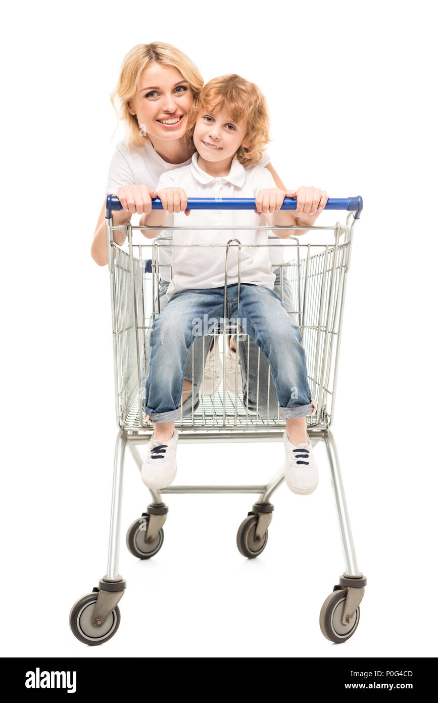 little boy sitting in shopping cart with smiling mother behind isolated ...