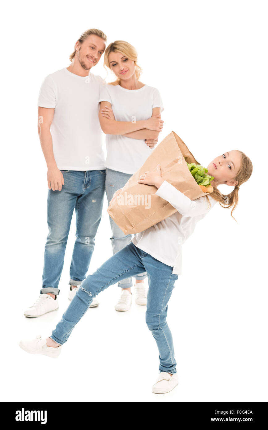 little girl holding heavy paper bag with food while parents standing ...