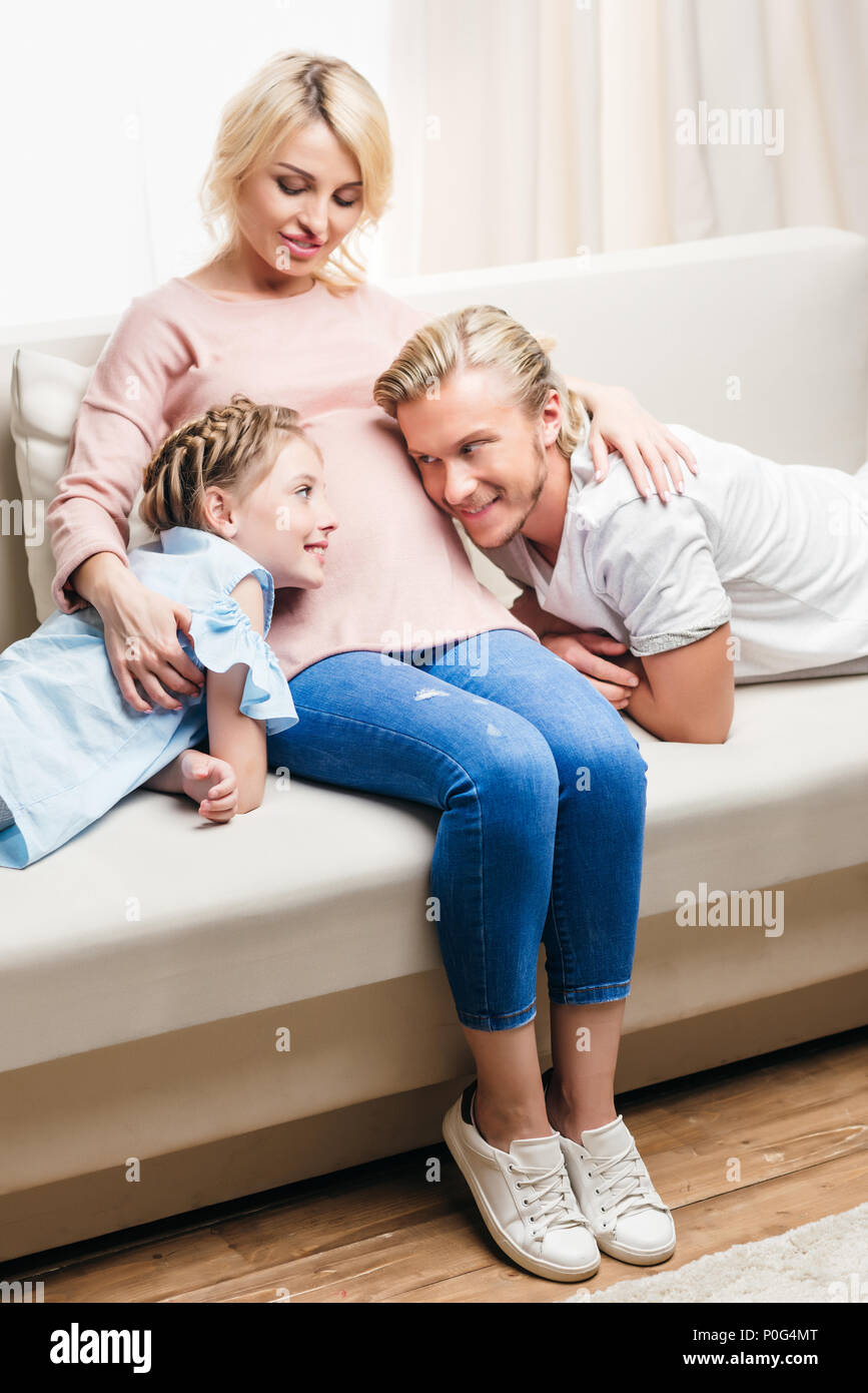 happy pregnant mother hugging husband and daughter while resting on ...
