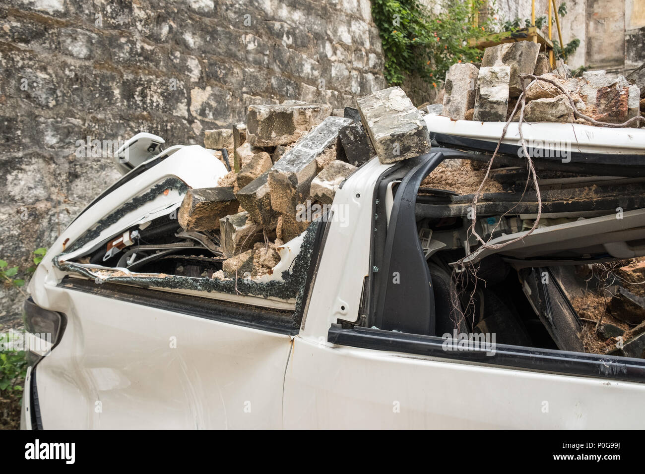 Broken white vehicle buried with old gray bricks from shattered wall ...