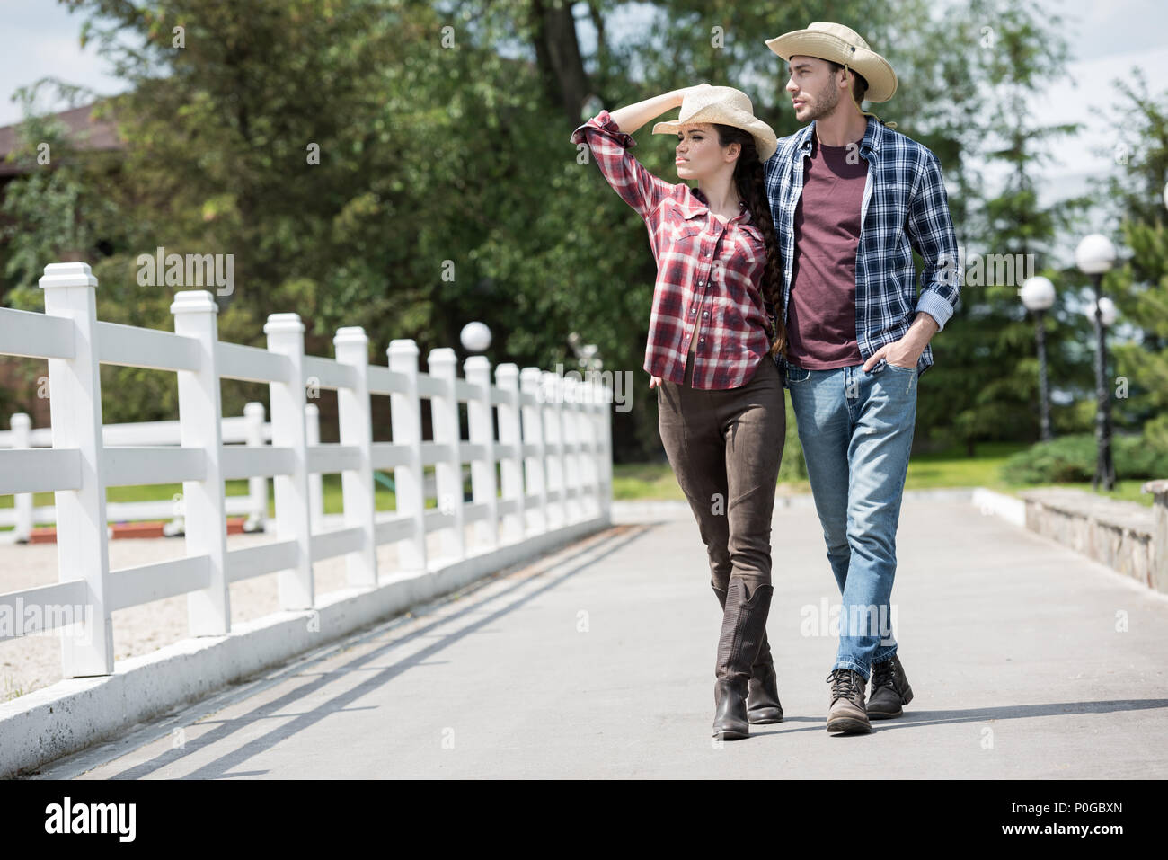 young cowboy with his girlfriend walking on pathway in park at daytime ...