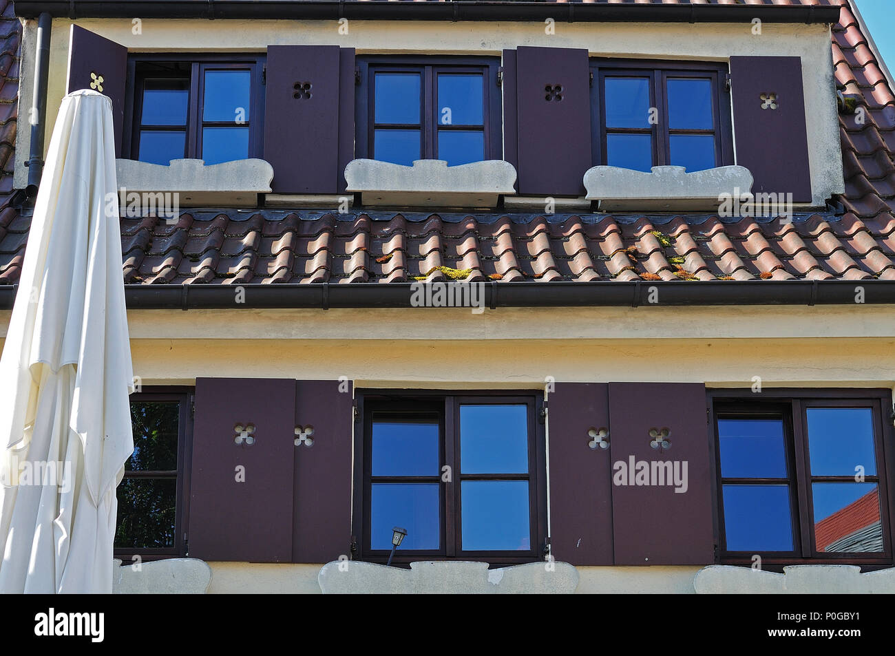 folded white parasol in front of traditional german house with mansard ...