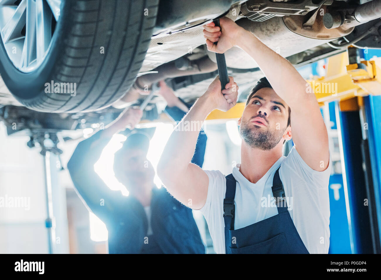 Two automechanics working on a car in a repair workshop Stock Photo - Alamy