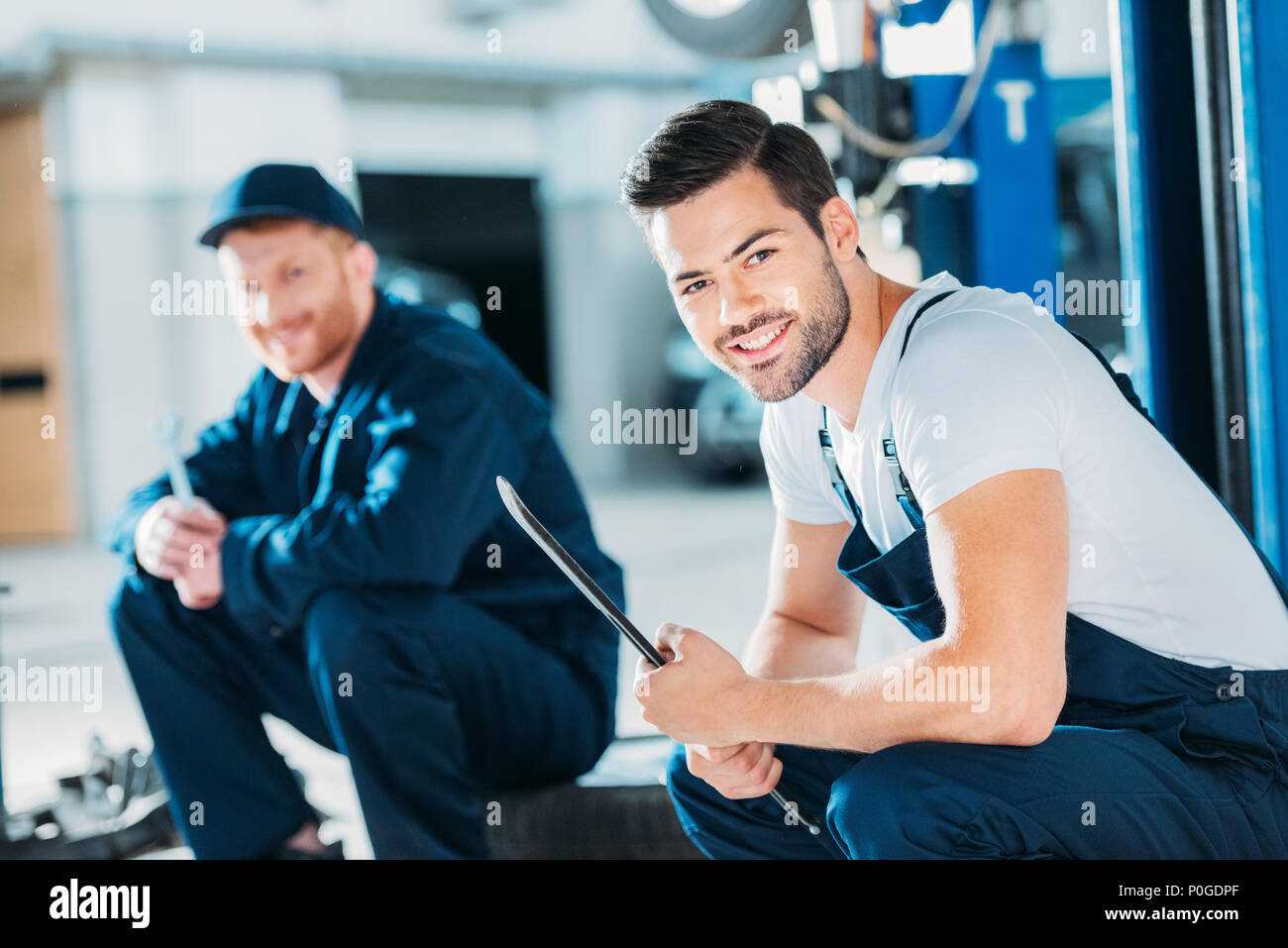Young automechanics sitting on a floor of a repair shop Stock Photo - Alamy