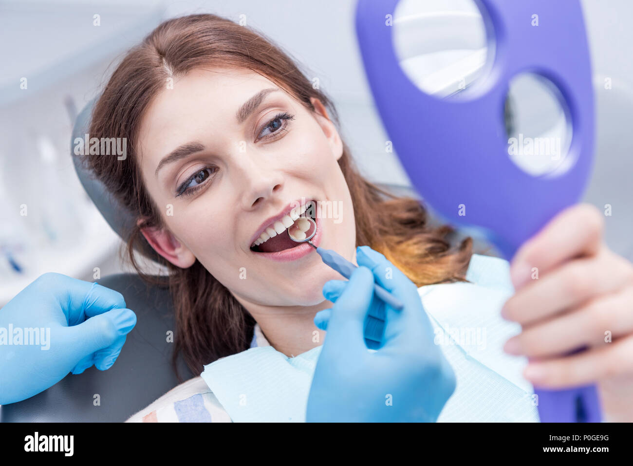 portrait of beautiful woman checking teeth after curing teeth in dental ...