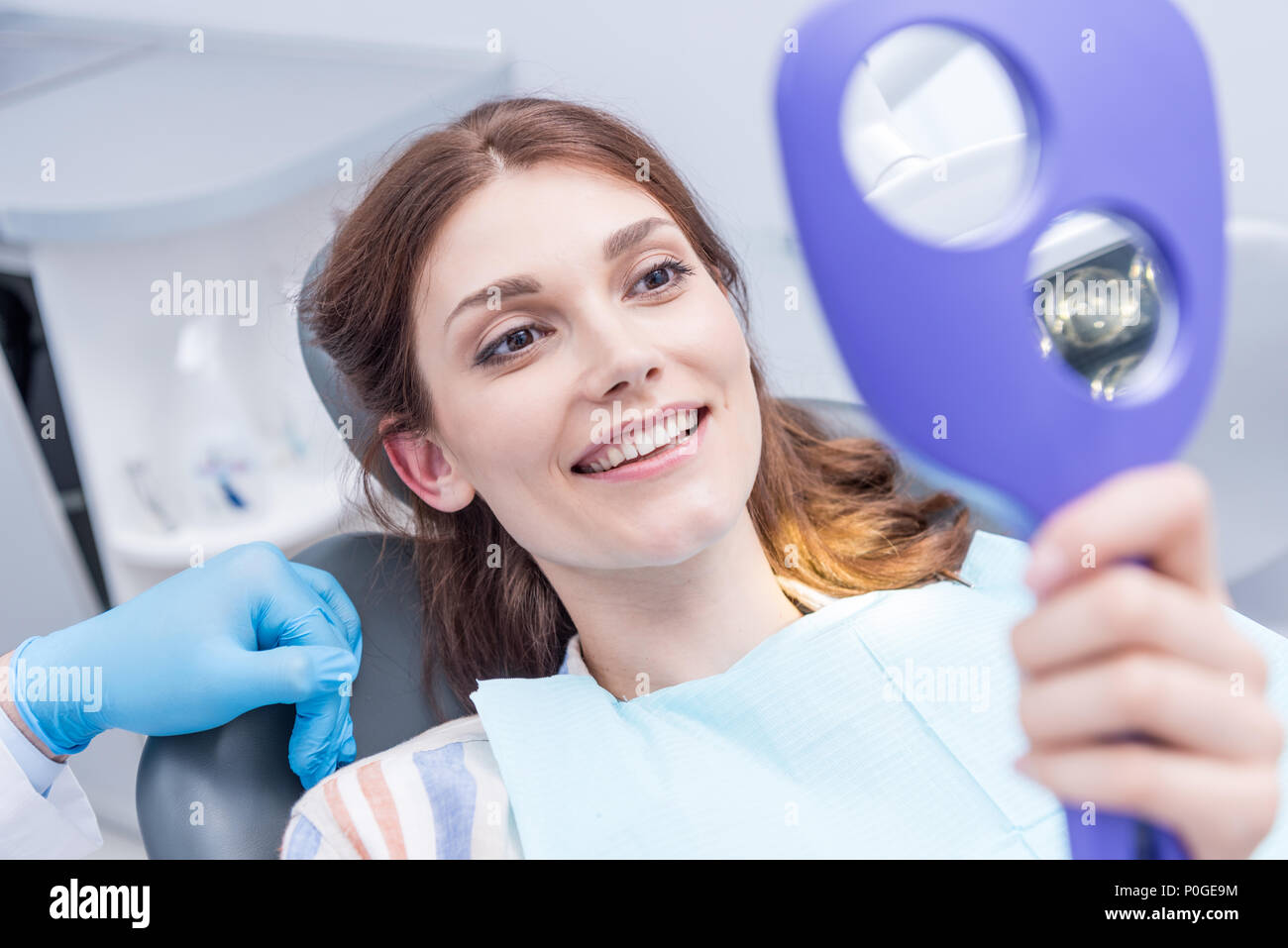 portrait of beautiful woman checking teeth after curing teeth in dental ...