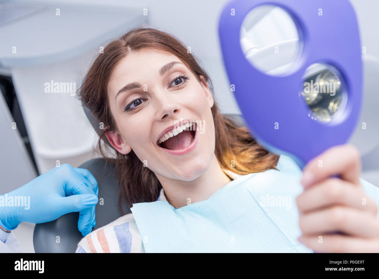 portrait of beautiful woman checking teeth after curing teeth in dental ...