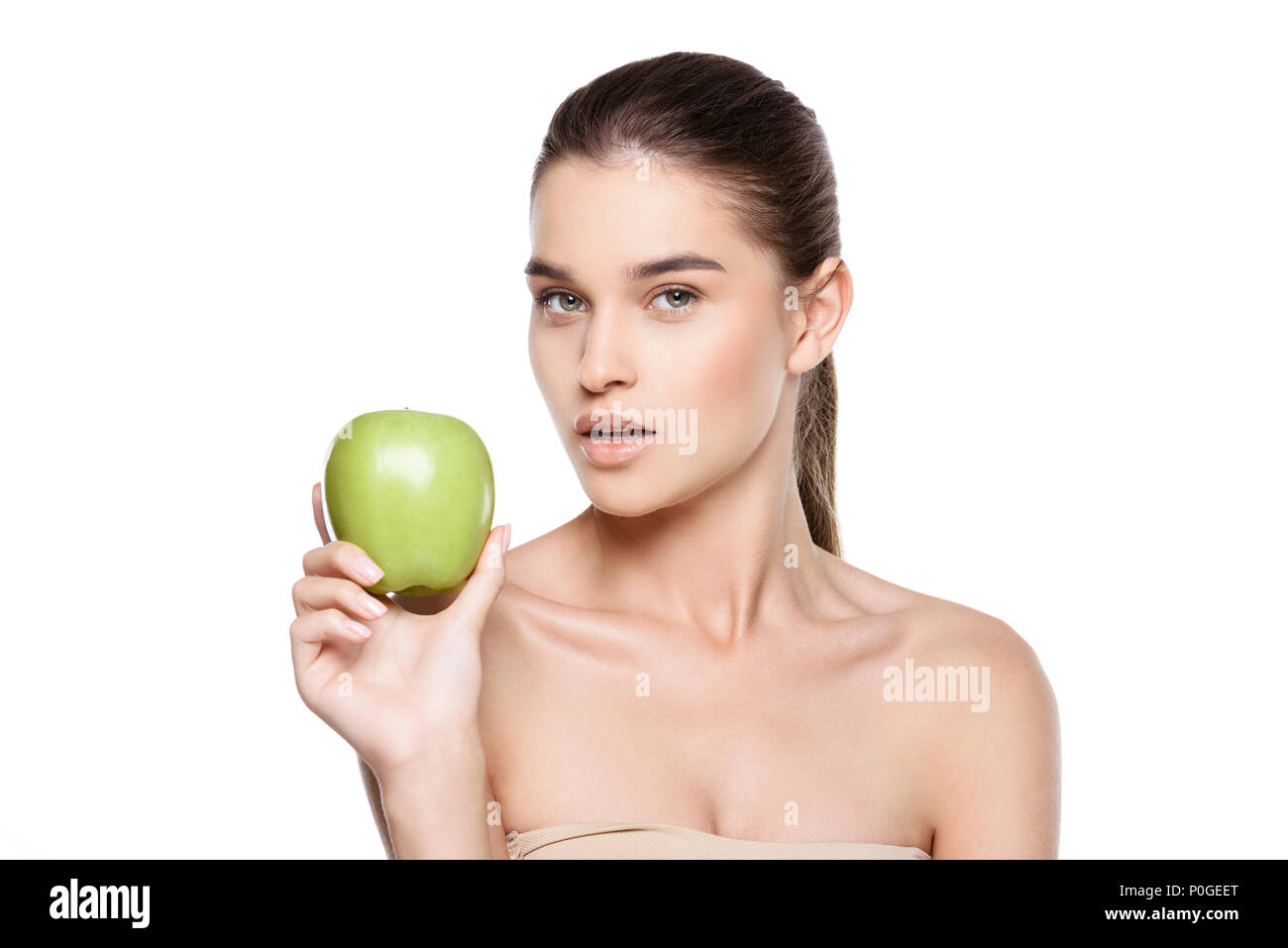Beautiful young woman holding green apple and posing at camera isolated ...