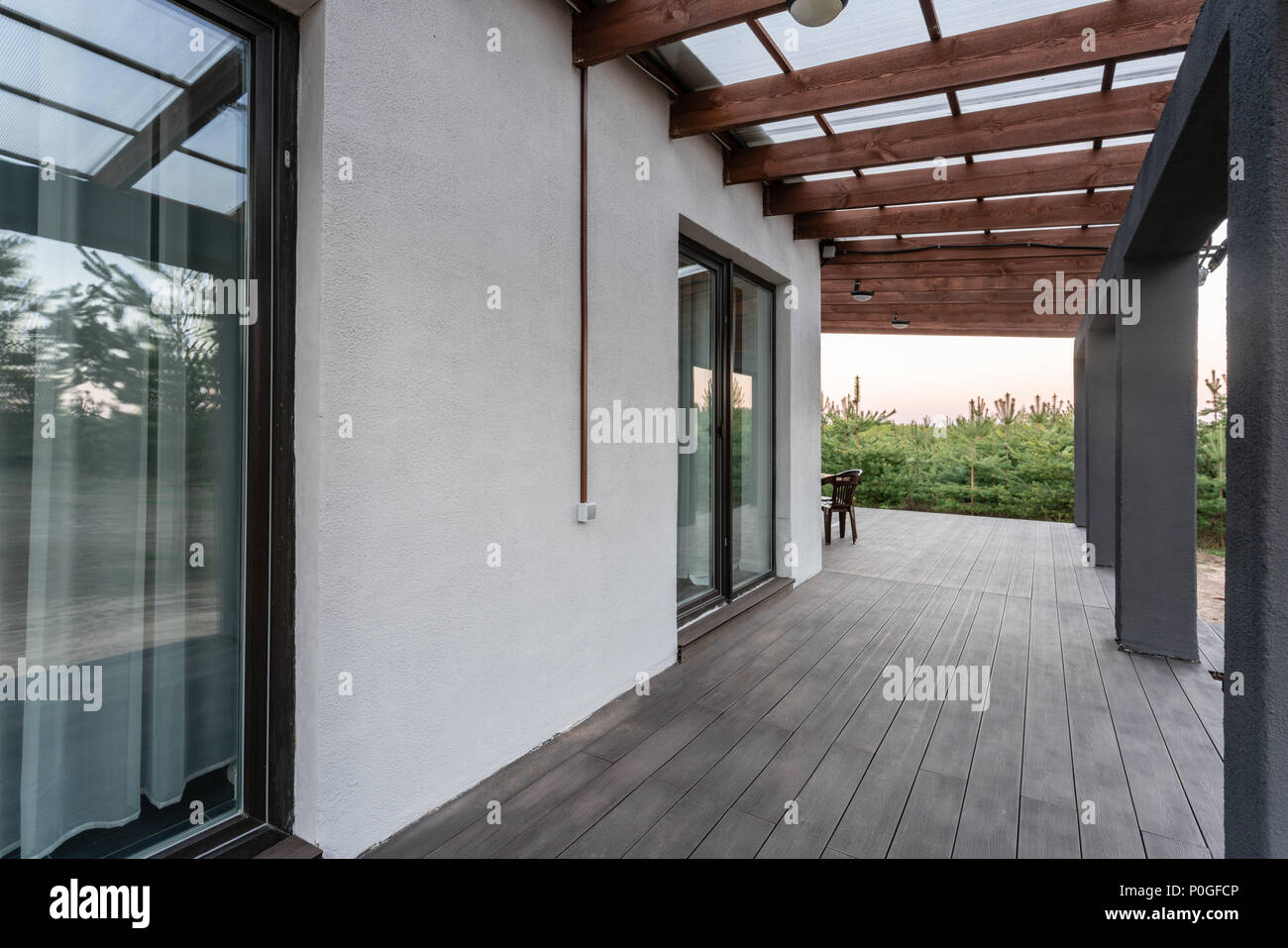 Side view of an open veranda in front of a modern forest cottage. Pine ...