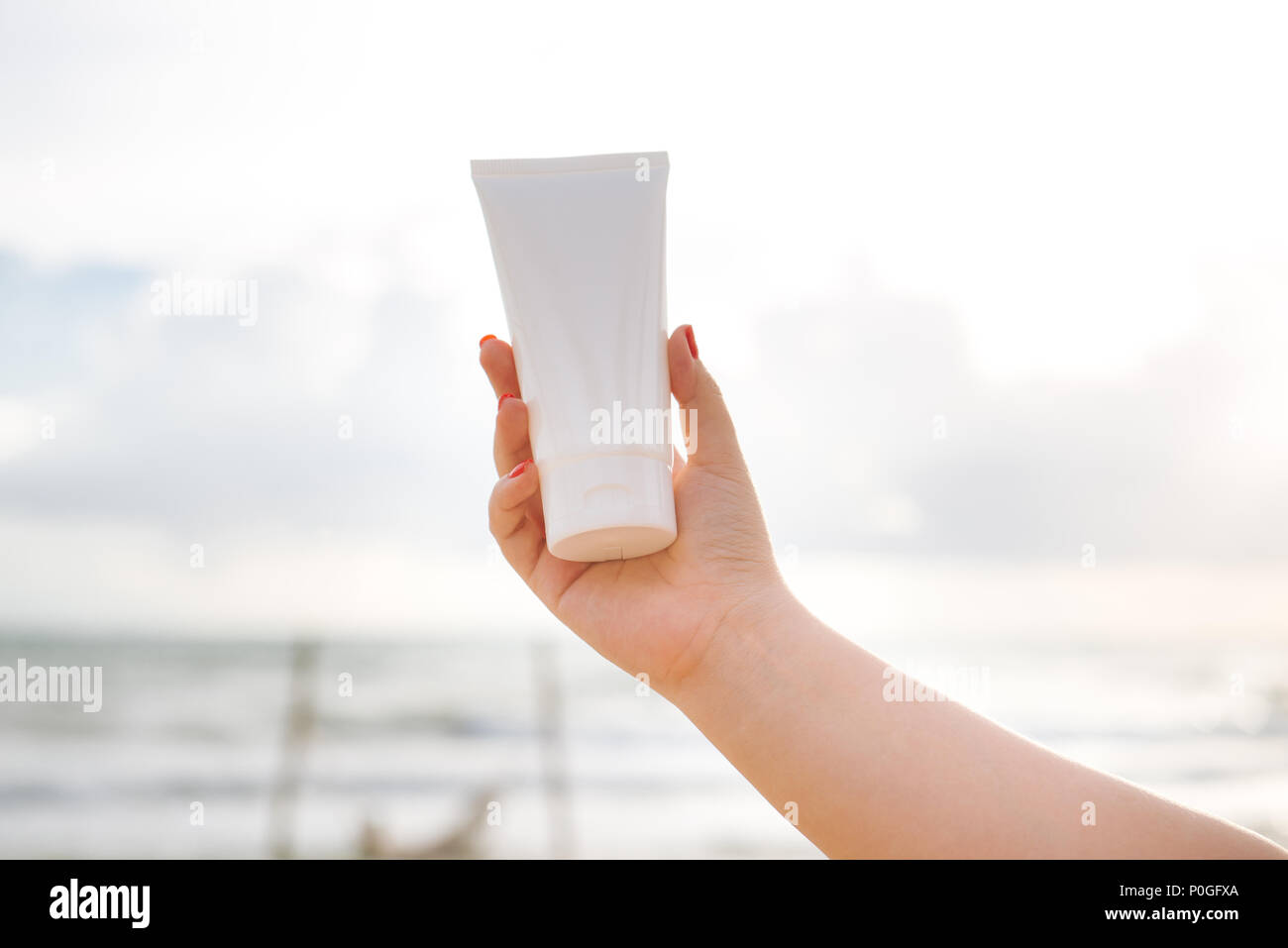 Woman hand holding sunscreen on the beach with the sea in blue sky ...