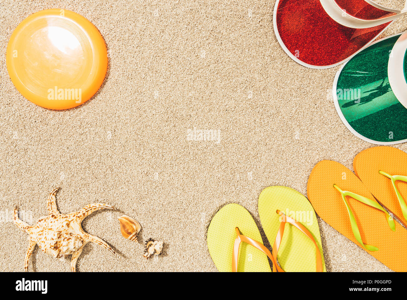 flat lay with flying disk, colorful caps, flip flops and seashells on ...