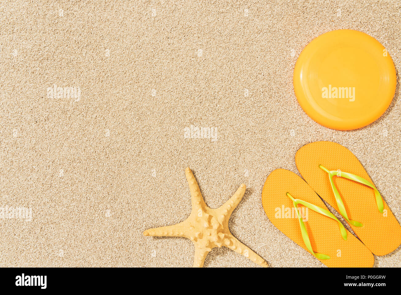 top view of sea star, yellow flip flops and flying disk on sand Stock ...