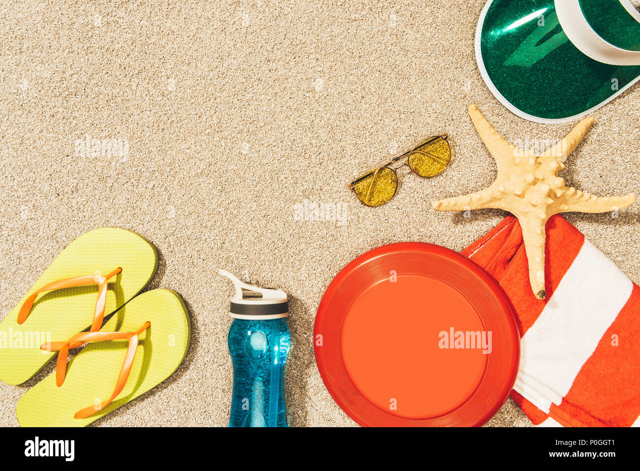 flat lay with frisbee, cap, flip flops, sunglasses and water bottle ...