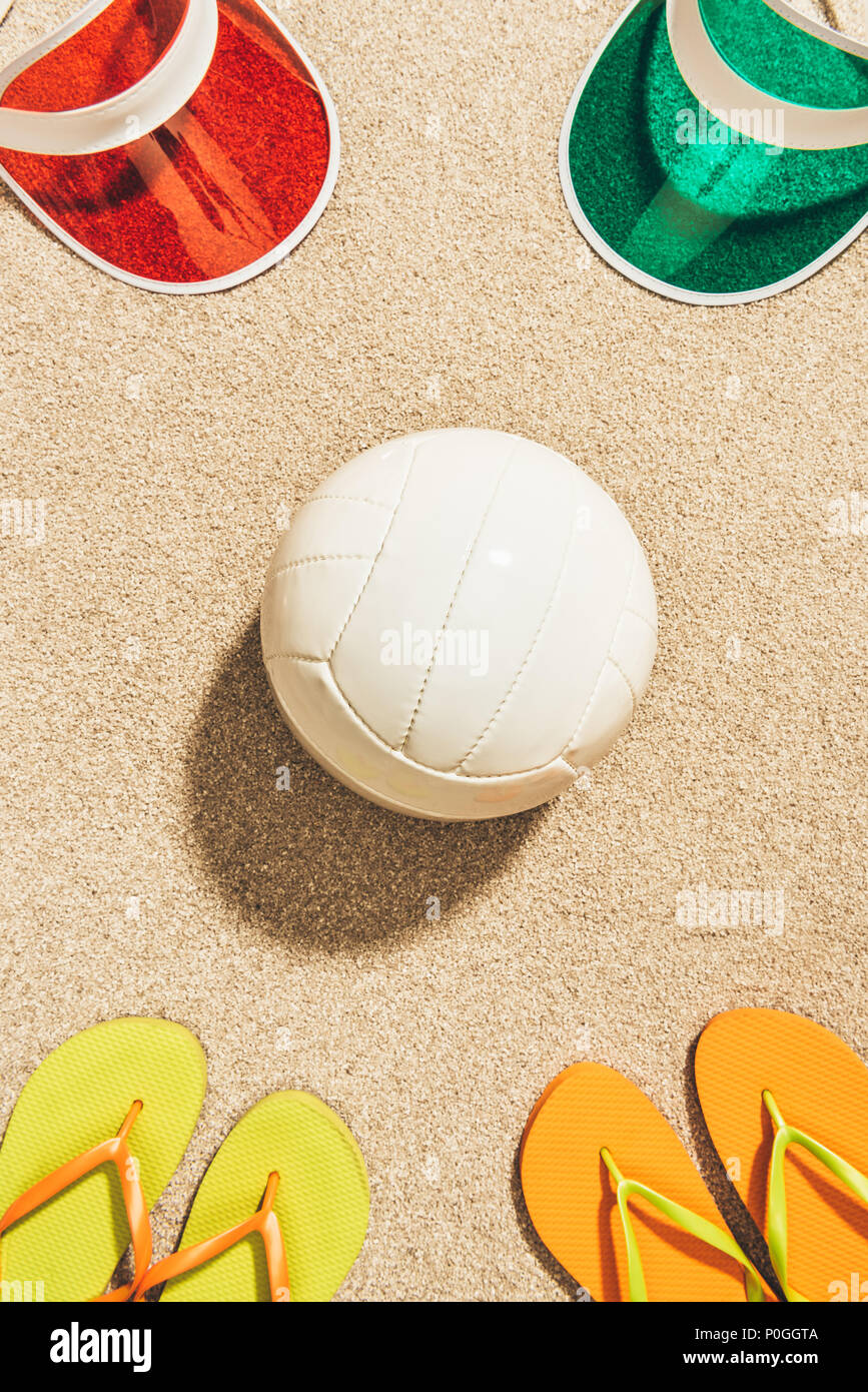 flat lay with white volleyball ball, colorful caps and flip flops ...