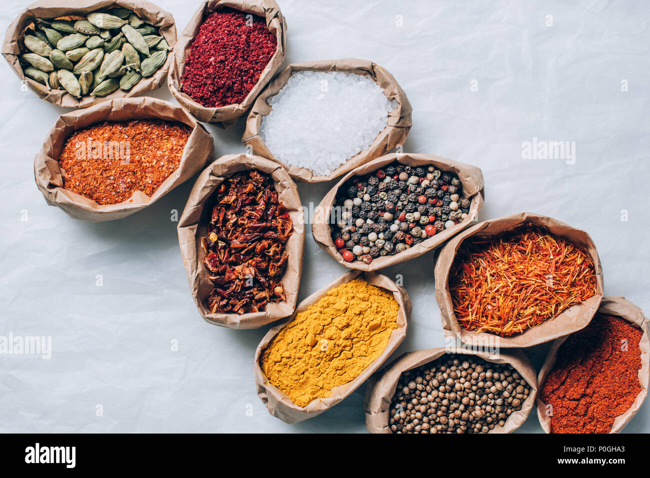 top view of colorful spices in paper bags on white table Stock Photo ...